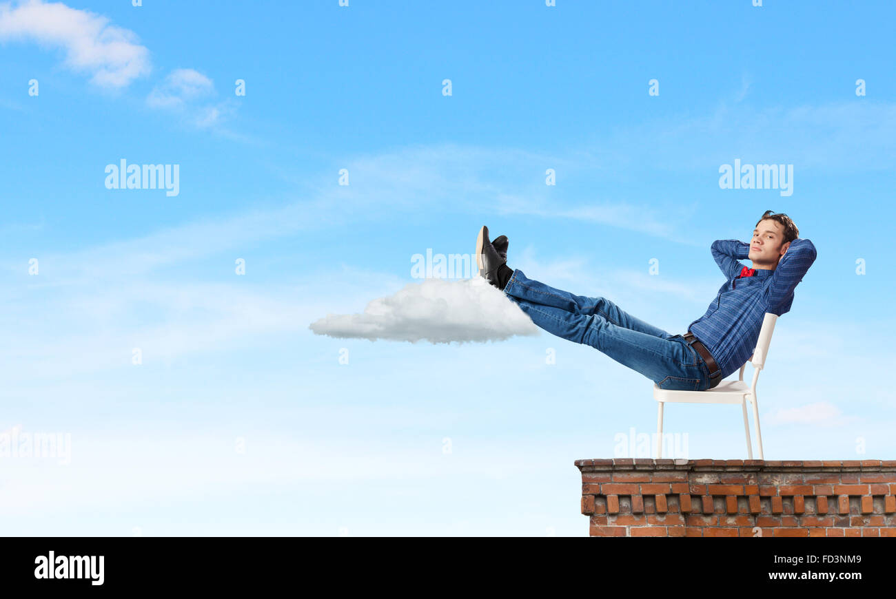 Young man sitting in chair with legs up and relaxing Stock Photo - Alamy
