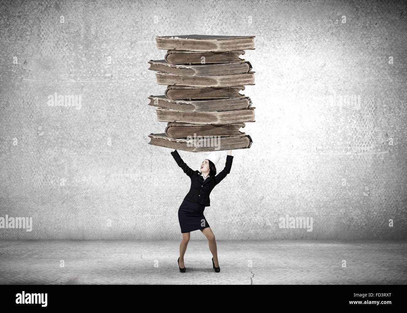 Young businesswoman in paper crown lifting books above head Stock Photo ...