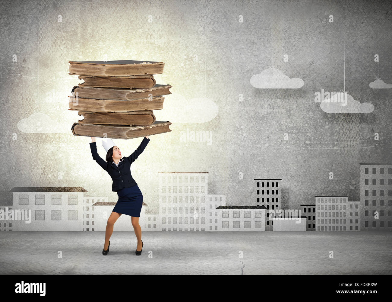 Young businesswoman in paper crown lifting books above head Stock Photo ...