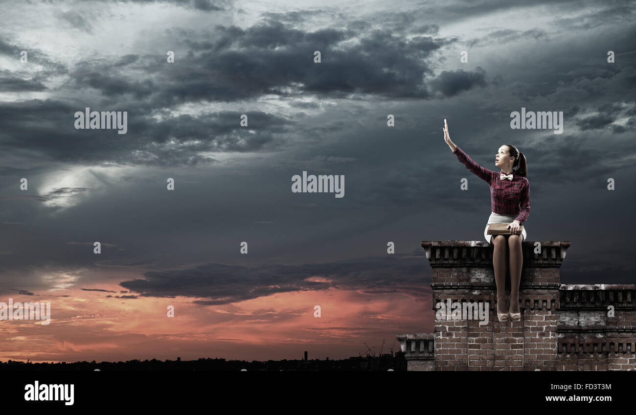 Young beautiful lady sitting on building roof and reading book Stock ...