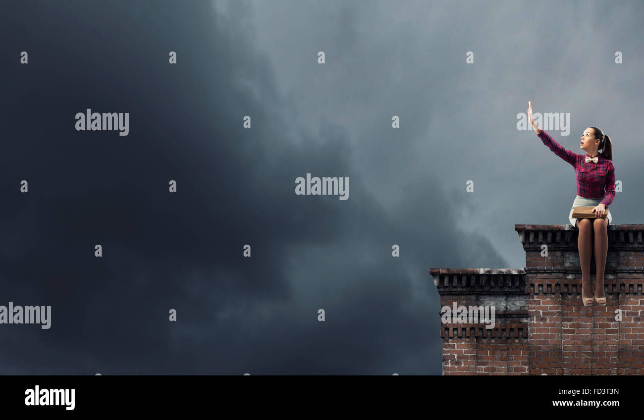Young beautiful lady sitting on building roof and reading book Stock ...