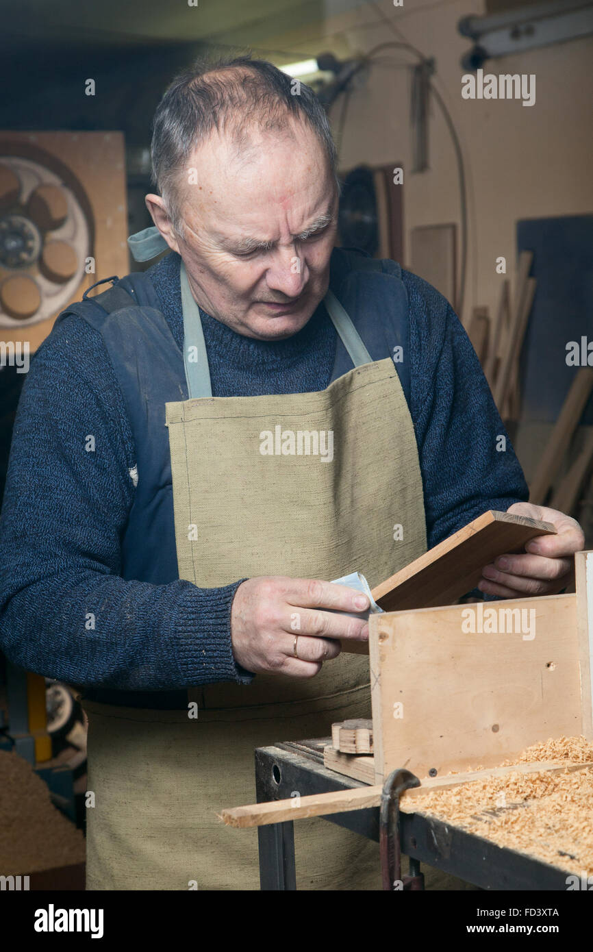 Men sandpaper grinds wood product in a workshop Stock Photo - Alamy
