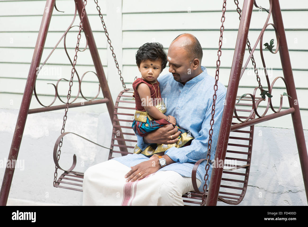 Indian father and daughter sitting on a swing. Traditional India family ...