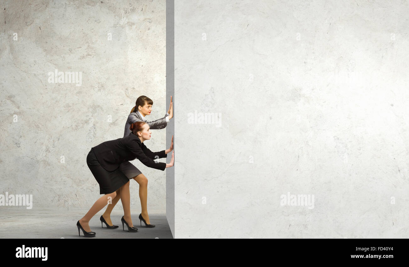 Two businesswoman pushing blank wall. Place for text Stock Photo - Alamy