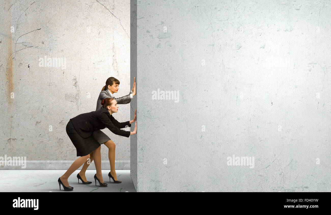 Two businesswoman pushing blank wall. Place for text Stock Photo - Alamy