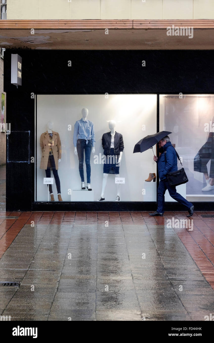 shopper in pouring rain walks past window display Stock Photo - Alamy