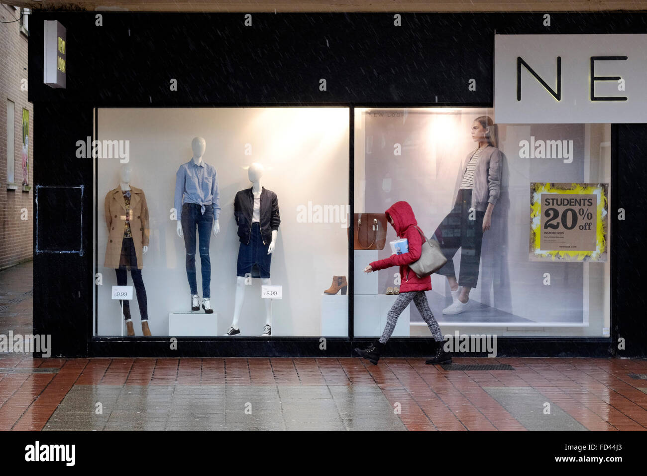 shopper in pouring rain walks past window display Stock Photo - Alamy
