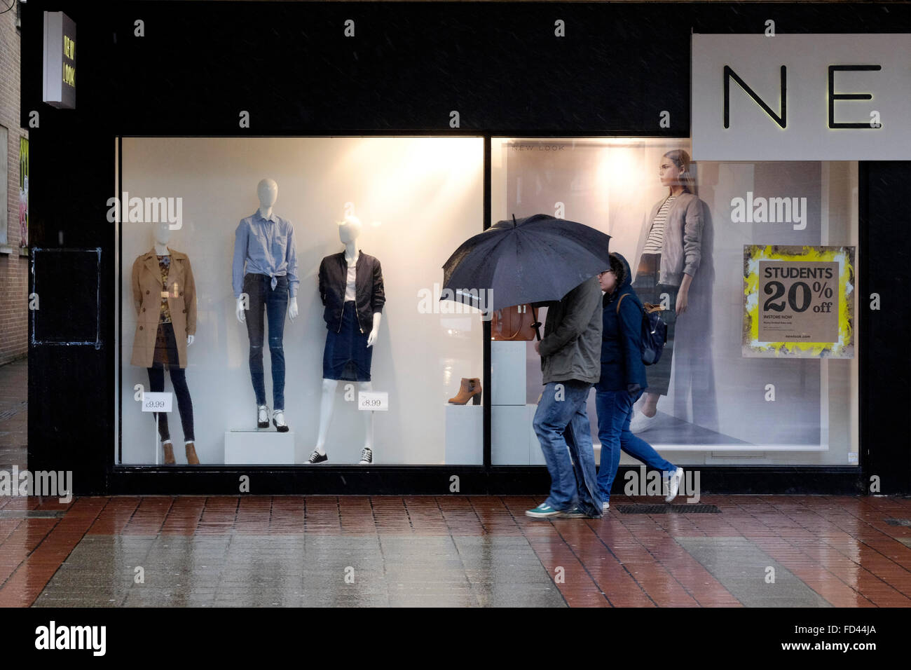 shoppers in pouring rain walks past window display Stock Photo - Alamy