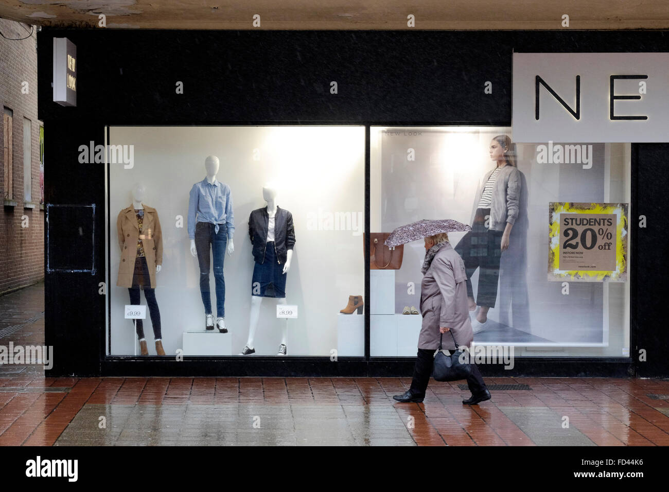 shopper in pouring rain walks past window display Stock Photo - Alamy