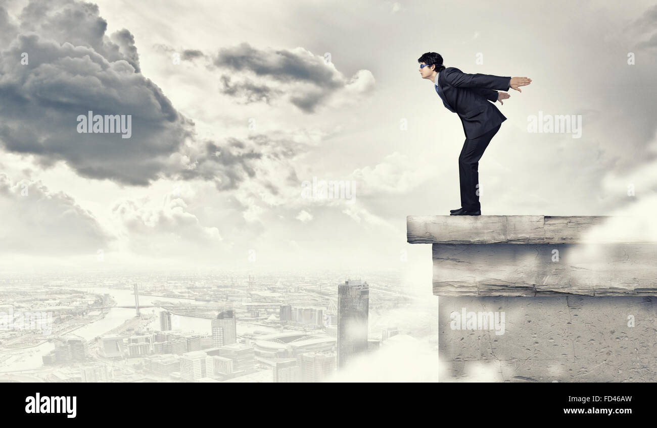 Image of young businessman in goggles jumping from top of building ...