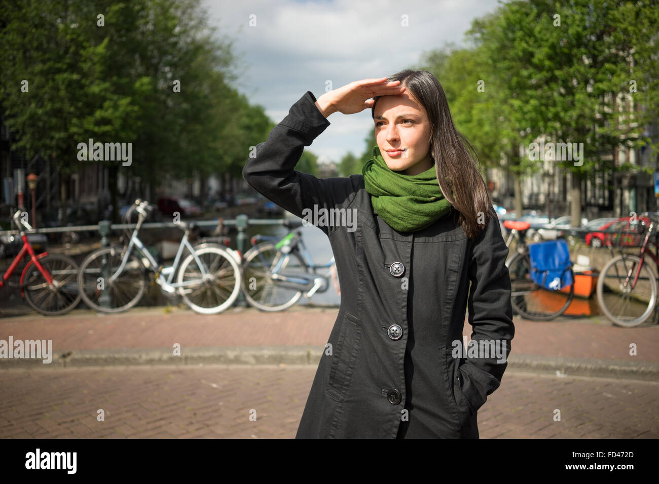 Beautiful young woman admiring the beauty of Amsterdam on a bridge ...