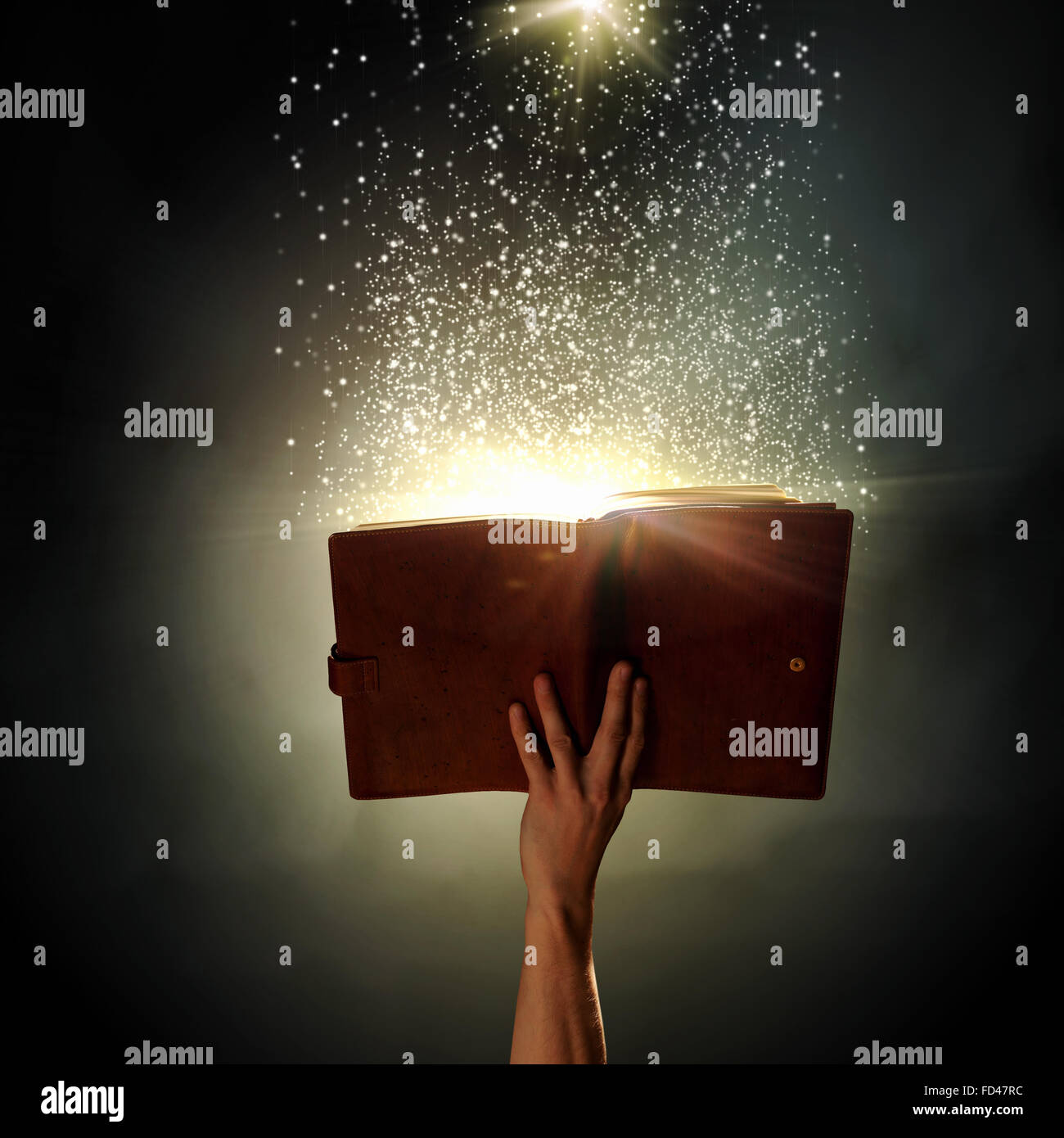 Human hand holding magic book with magic lights Stock Photo - Alamy
