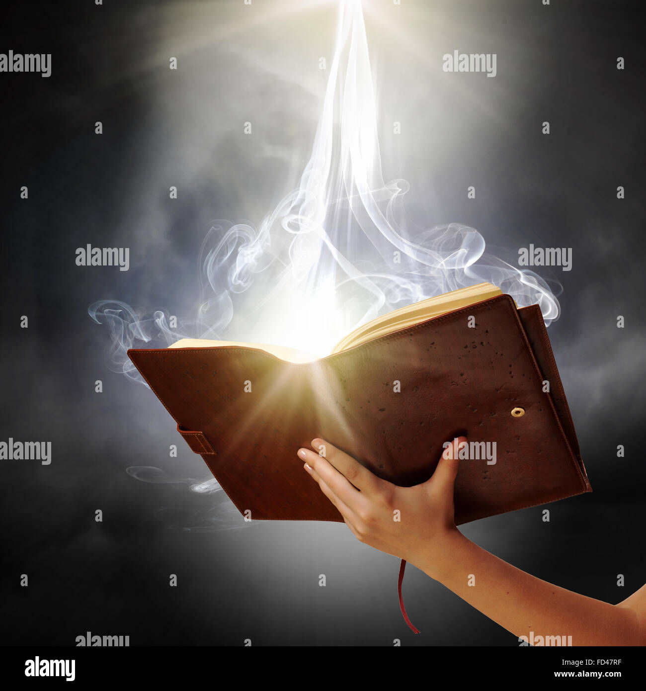 Human hand holding magic book with magic lights Stock Photo - Alamy