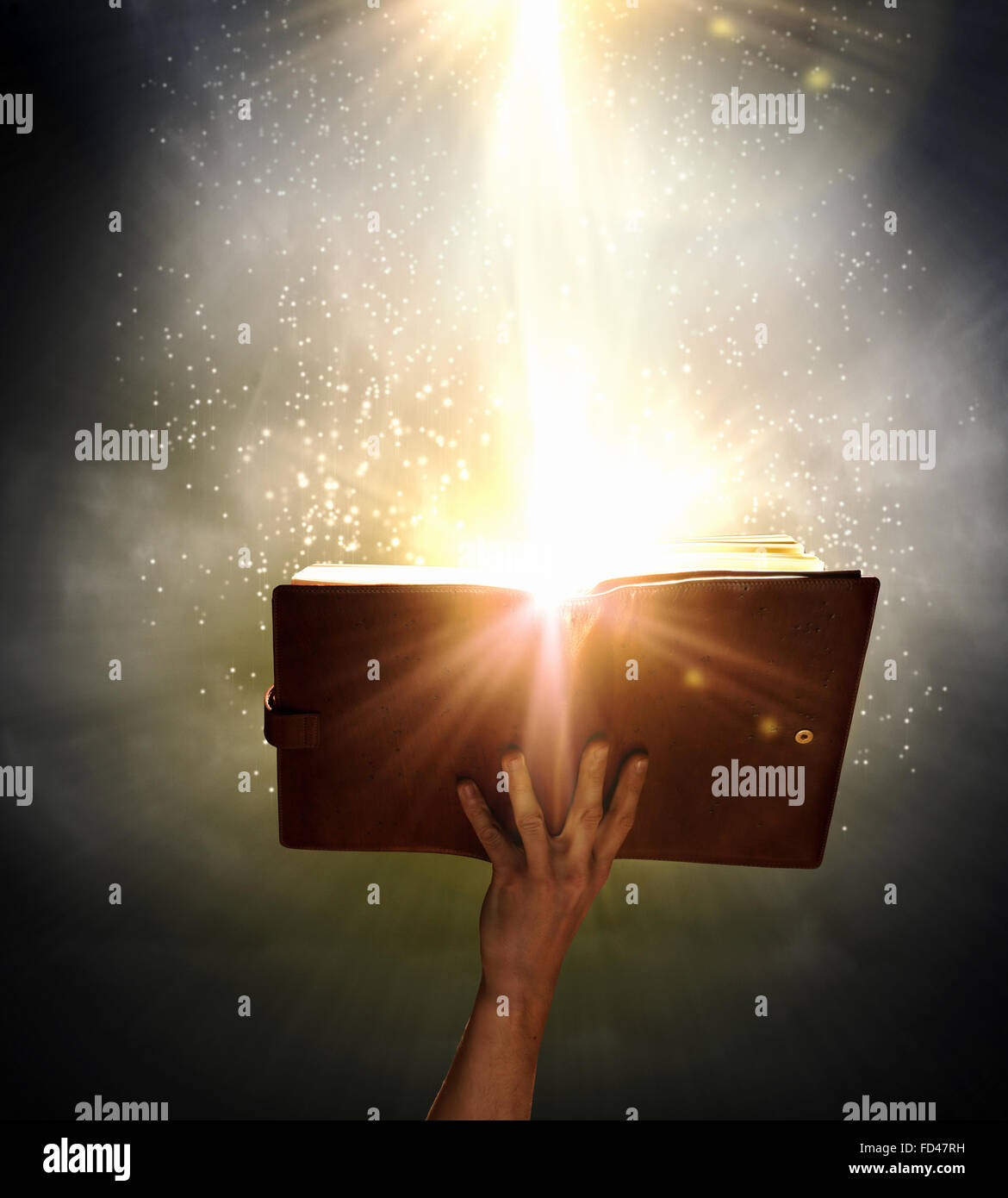 Human hand holding magic book with magic lights Stock Photo - Alamy