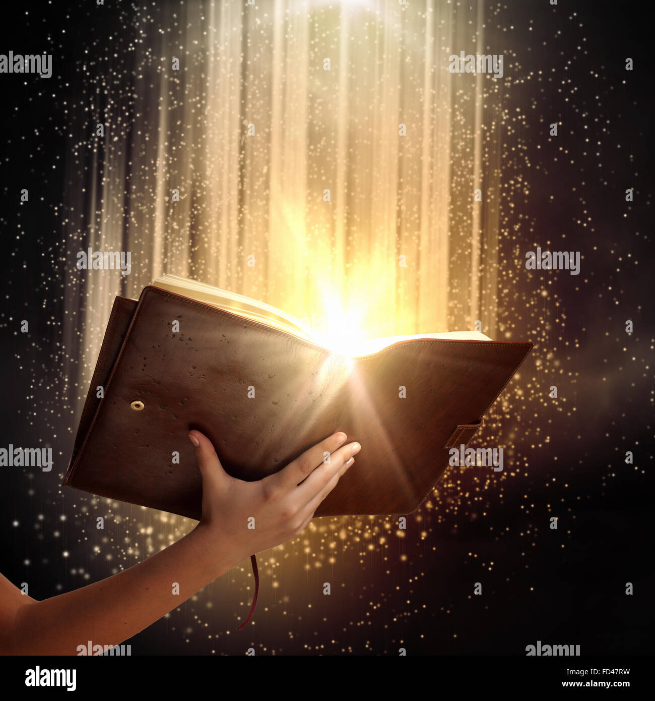 Human hand holding magic book with magic lights Stock Photo - Alamy