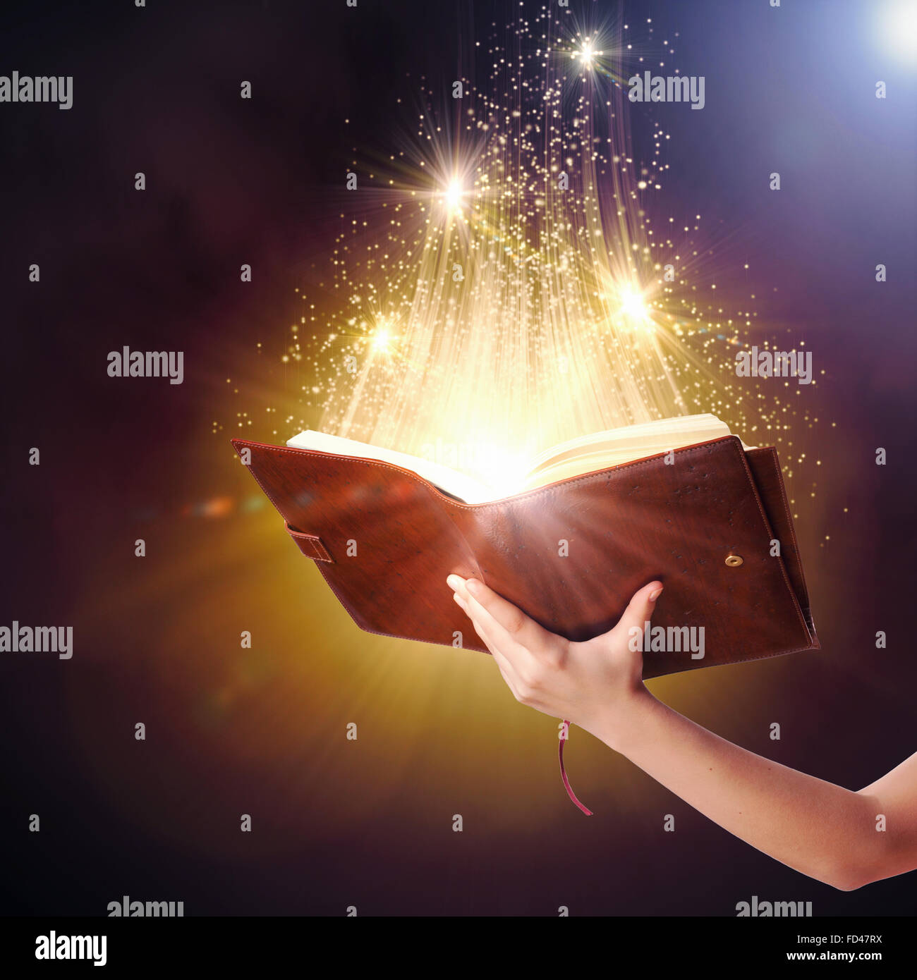 Human hand holding magic book with magic lights Stock Photo - Alamy