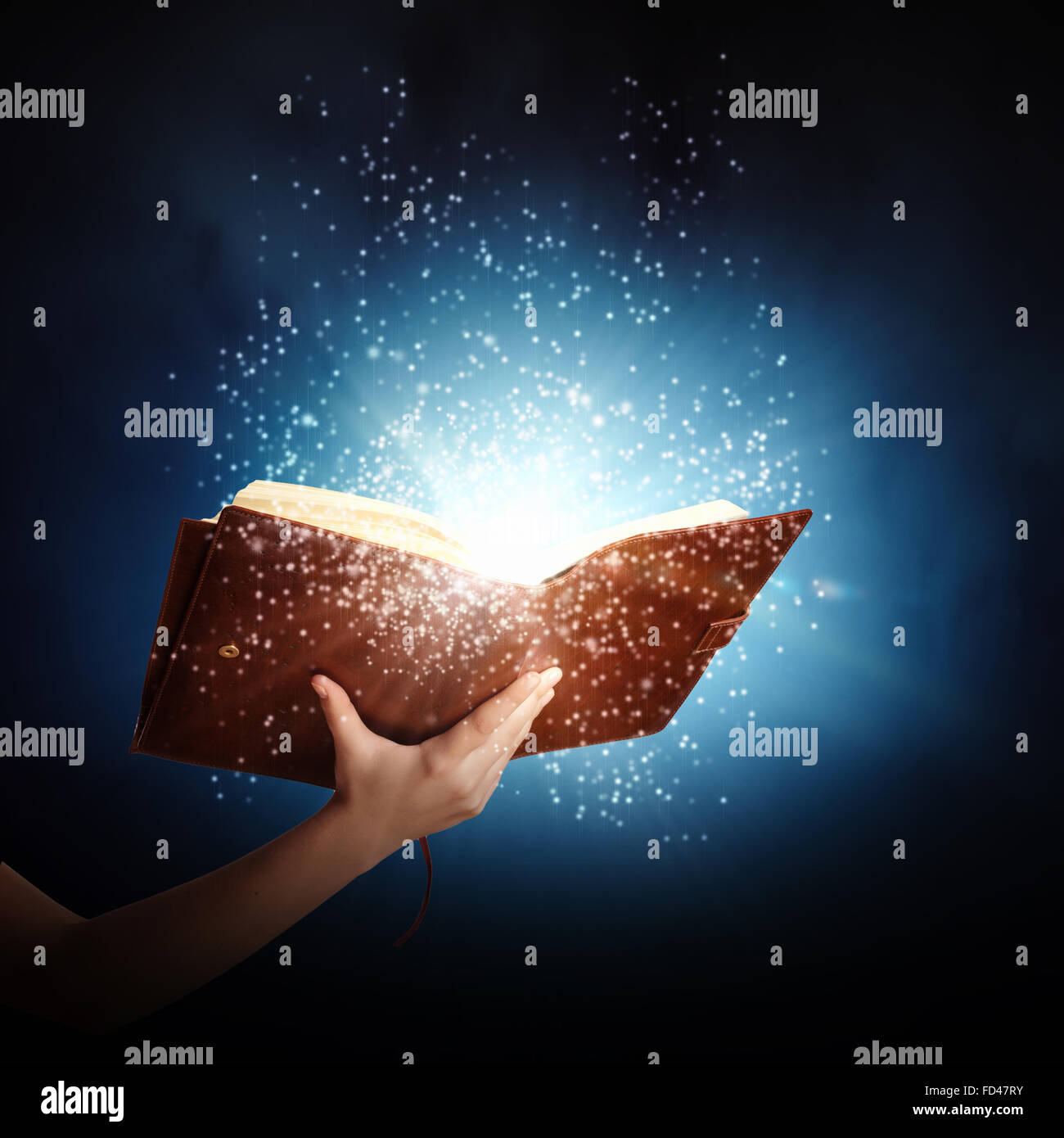 Human hand holding magic book with magic lights Stock Photo - Alamy