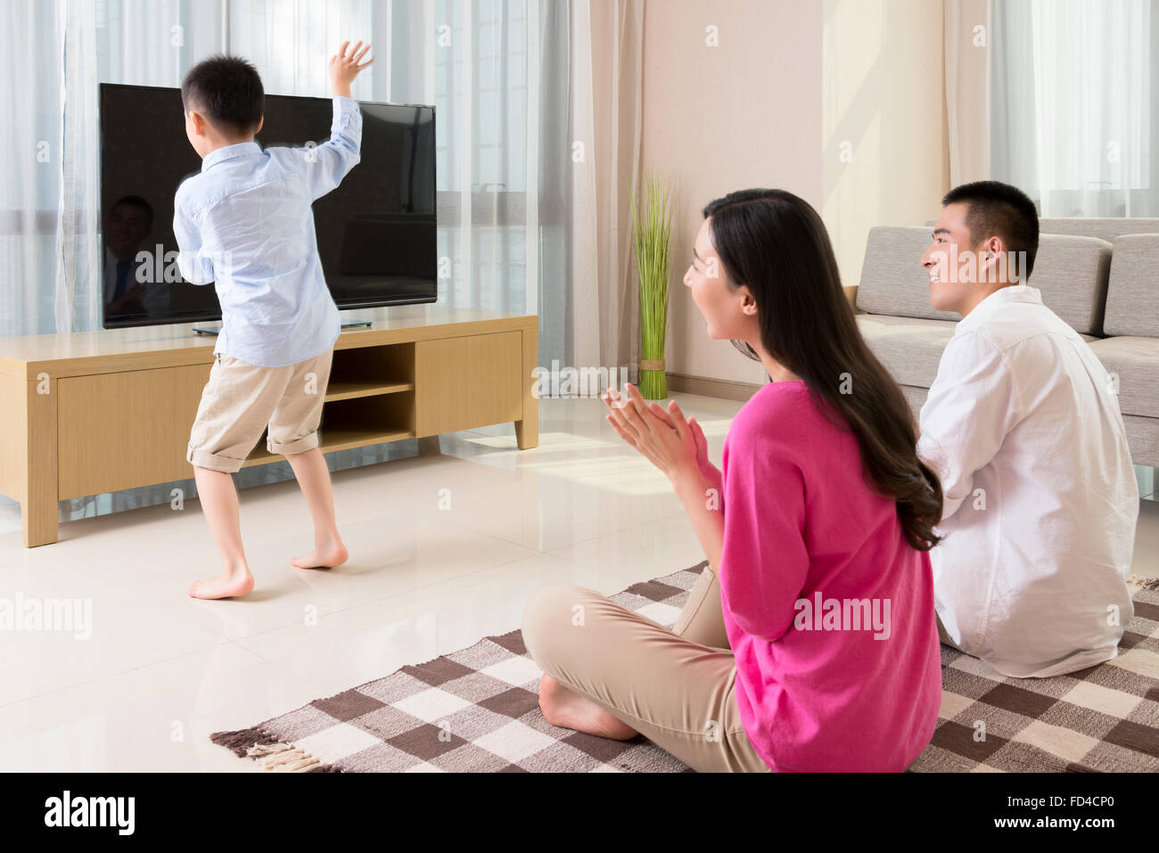 Parents watching son dancing with TV Stock Photo - Alamy