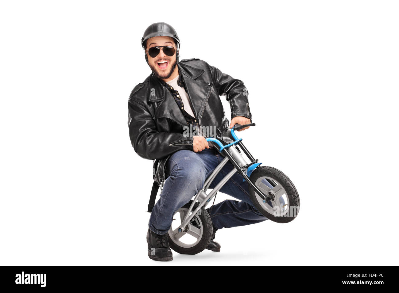 Silly young male biker sitting on a small toy bicycle and looking at ...