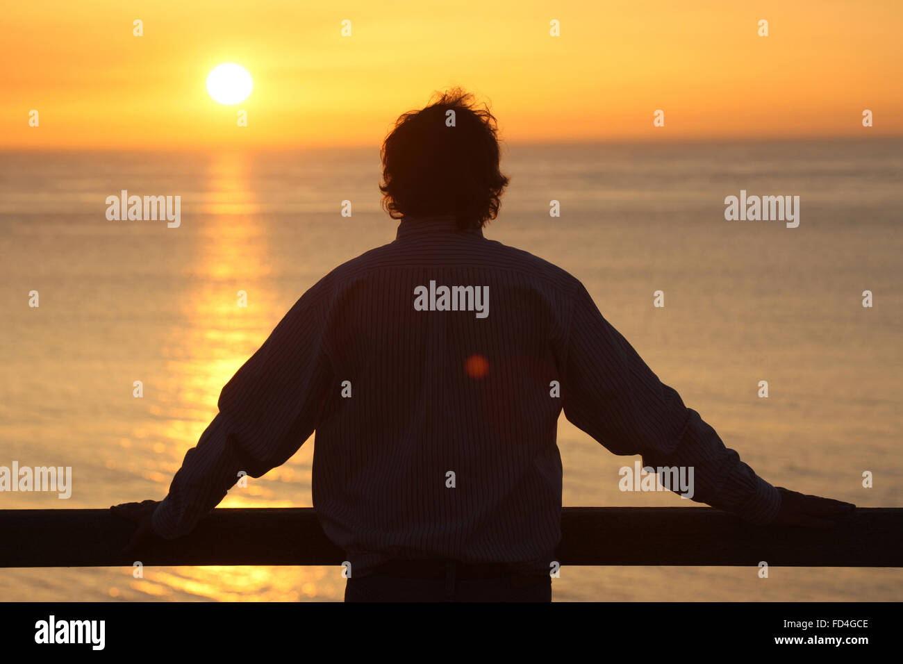 Man watching the sunset over the sea Stock Photo - Alamy