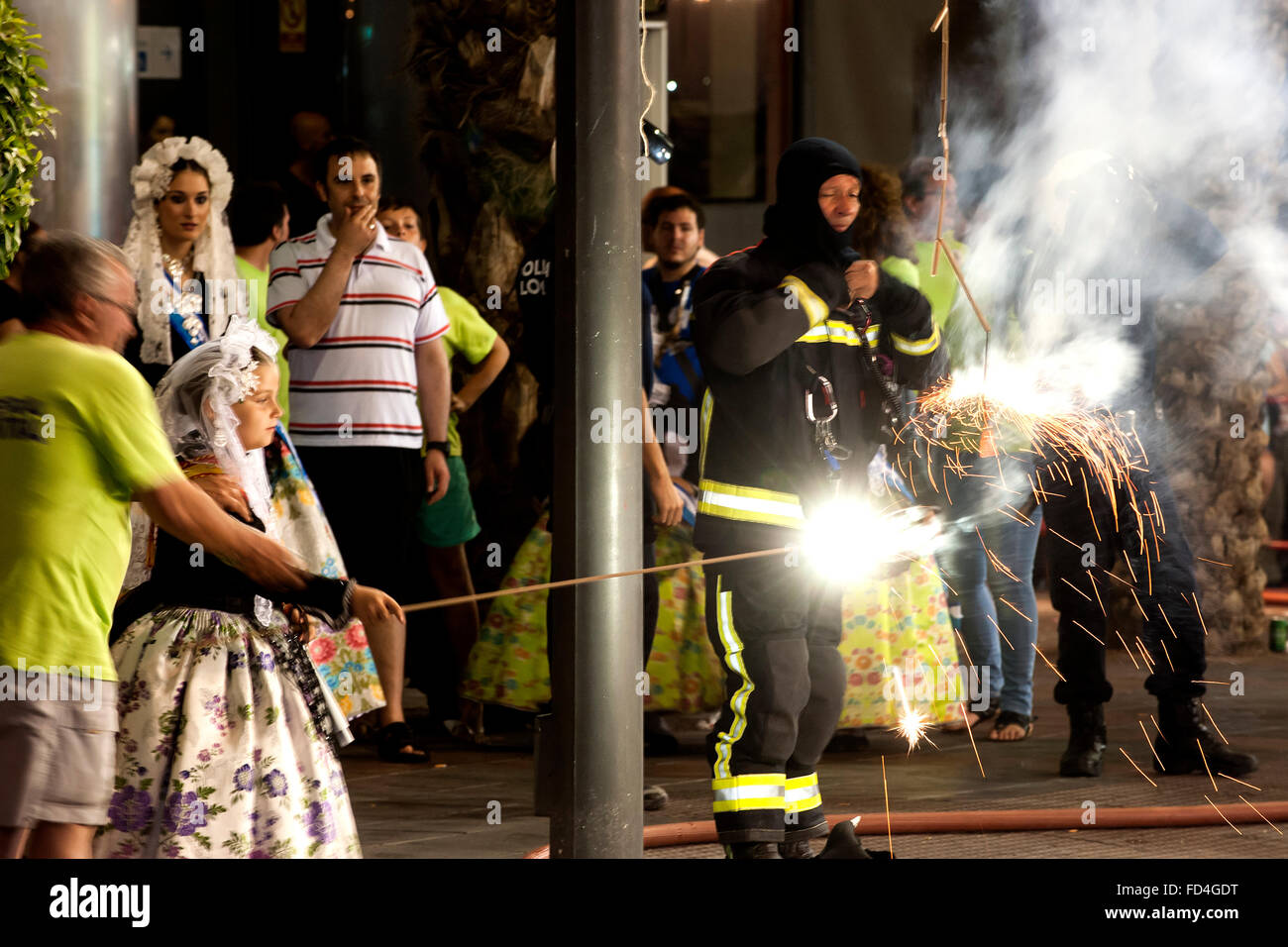 A girl lights the firecrackers fireworks with which to start the cremá ...