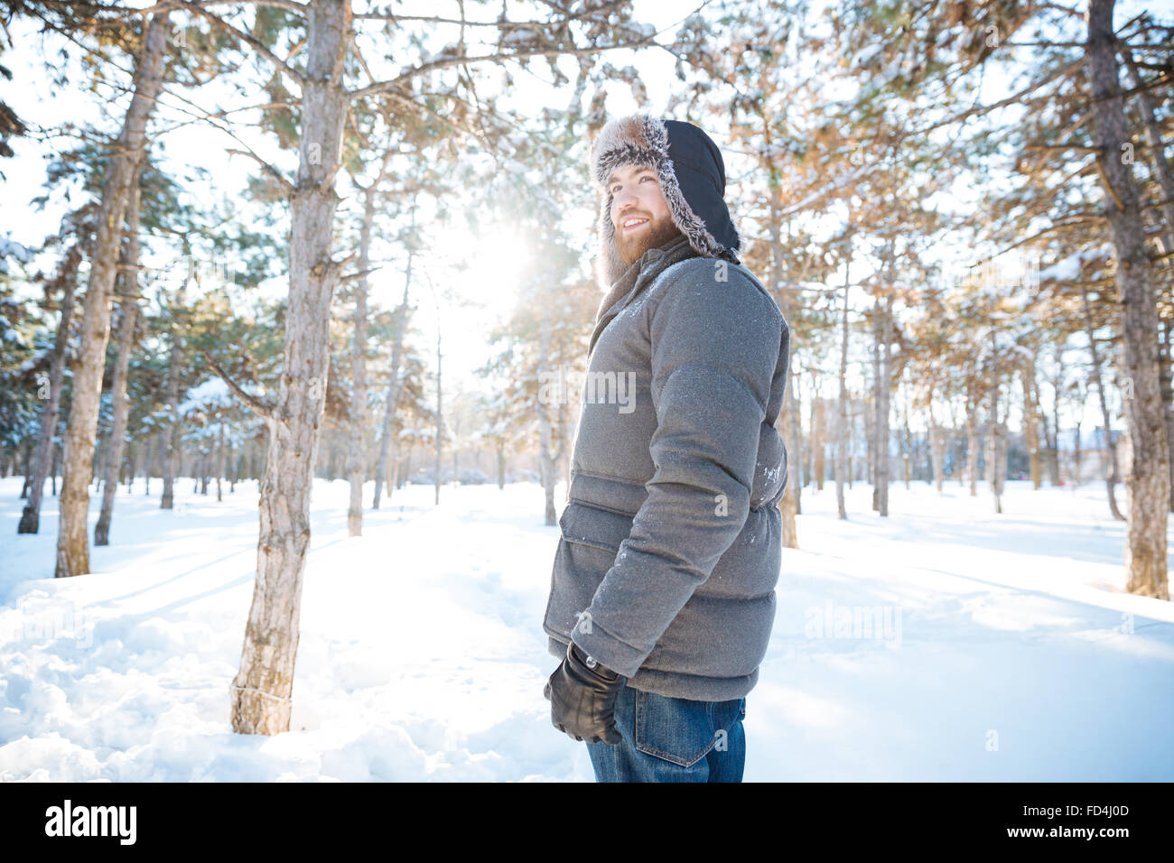Portrait of cheerful attractive young man in warm clothes standing in ...