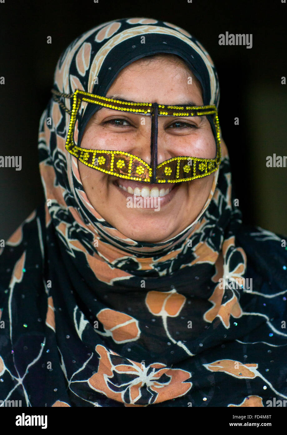 a smiling bandari woman wearing a traditional mask called the burqa ...