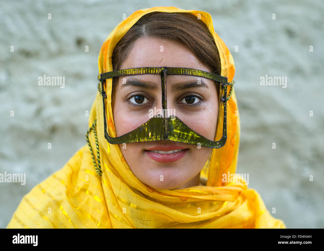 a smiling bandari woman wearing a traditional mask called the burqa ...