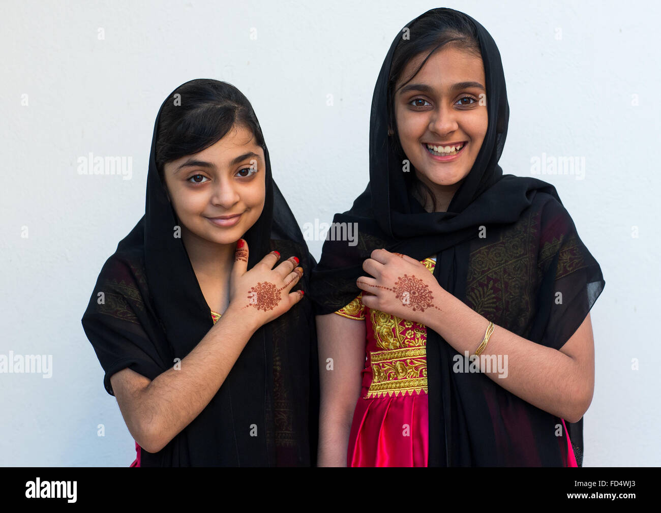 portrait of two young girls with henna tattooed hands in traditional ...
