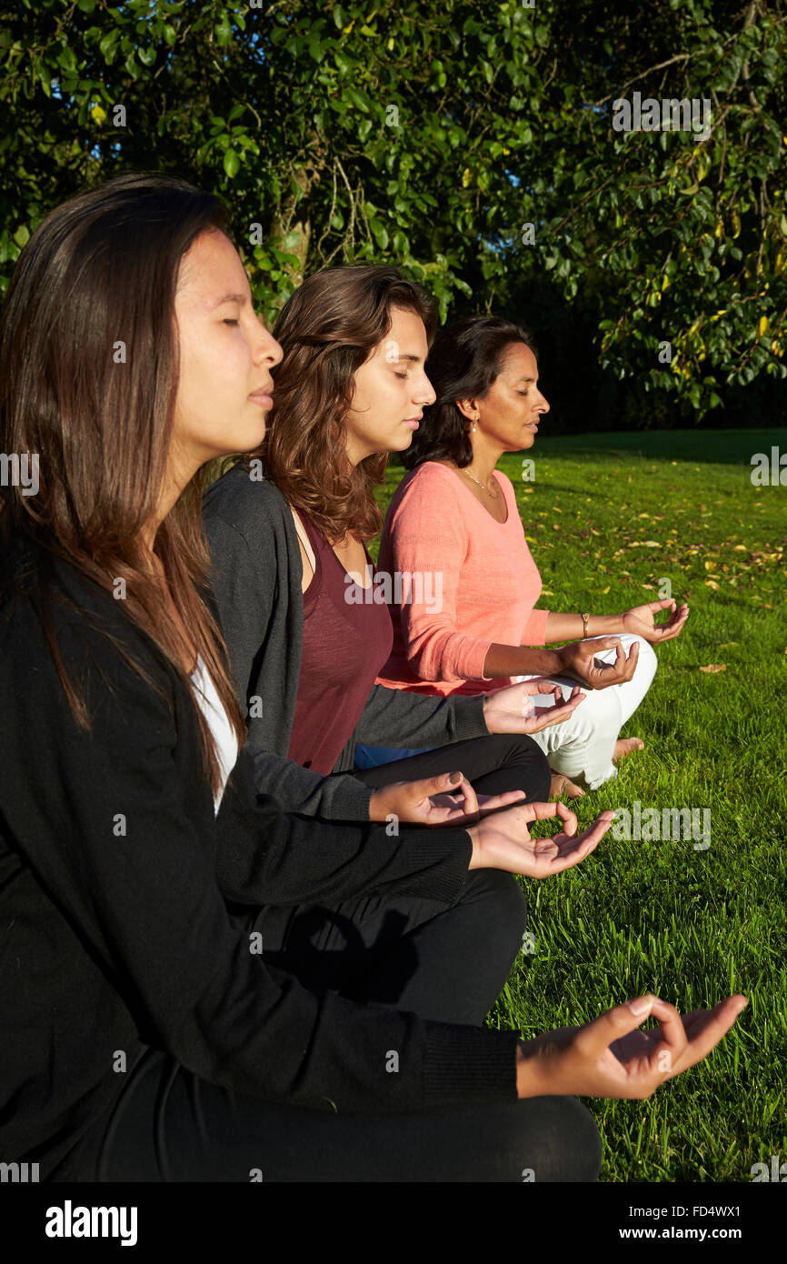 Teenagers and adult practising meditation Stock Photo - Alamy