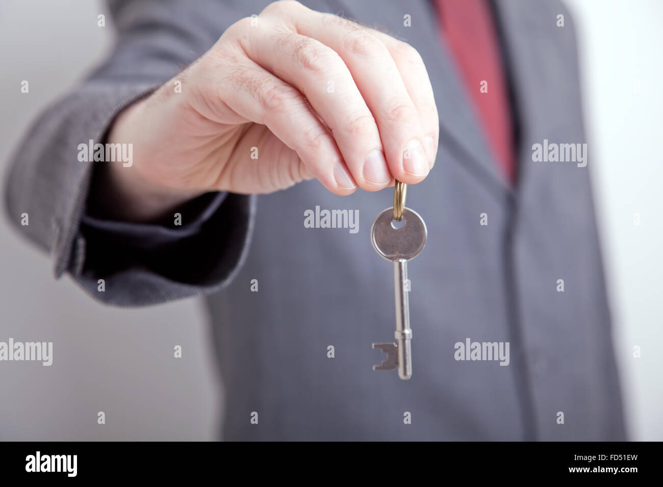 Landlord/ Realtor holding out a key to your new home Stock Photo - Alamy