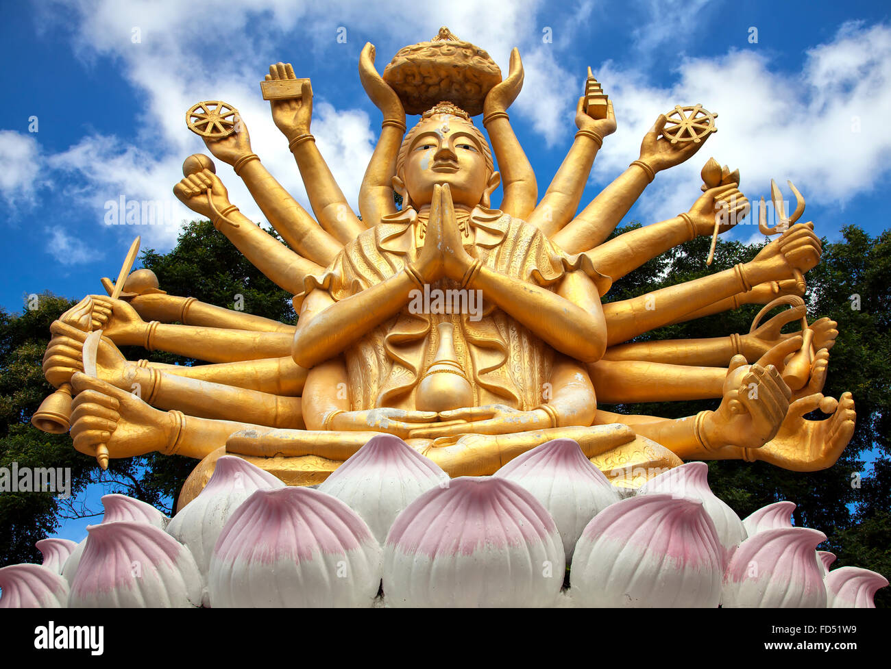 A huge statue of a multi armed Buddha sits on a hill near to the city ...