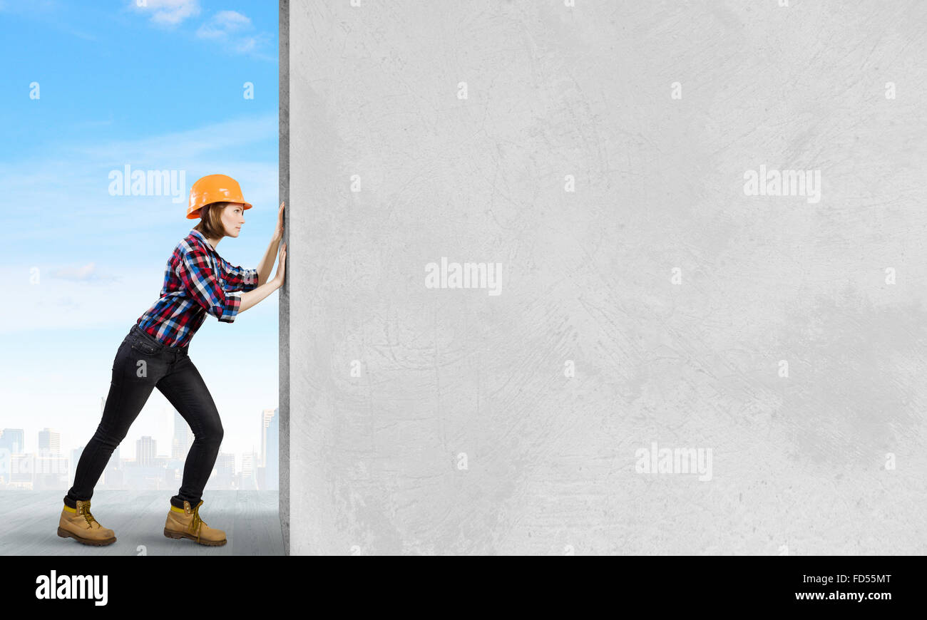 Image of young woman builder wearing helmet and pulling blank wall ...