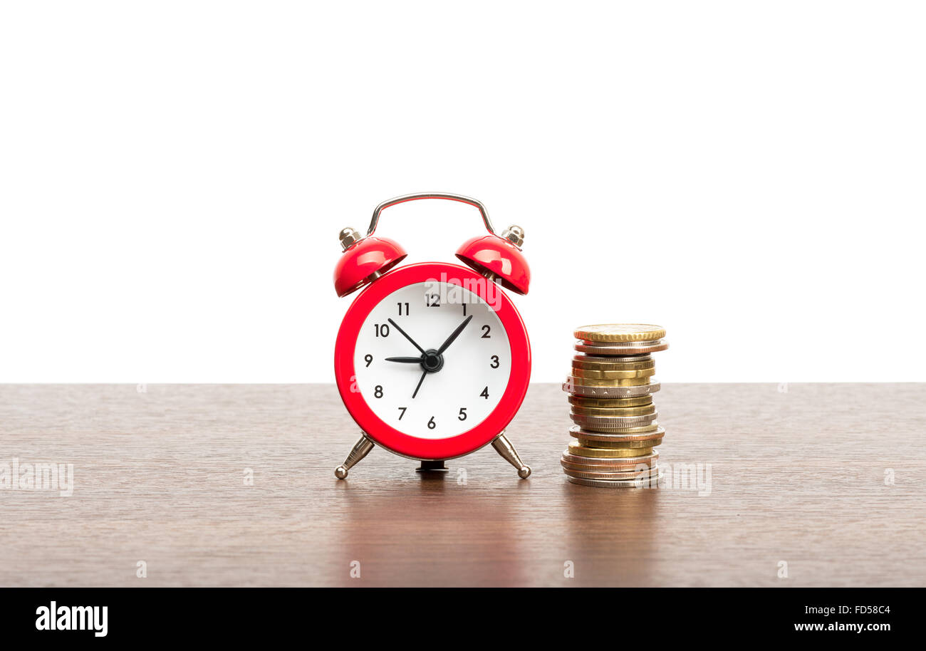 Alarm clock with stack of coins Stock Photo - Alamy