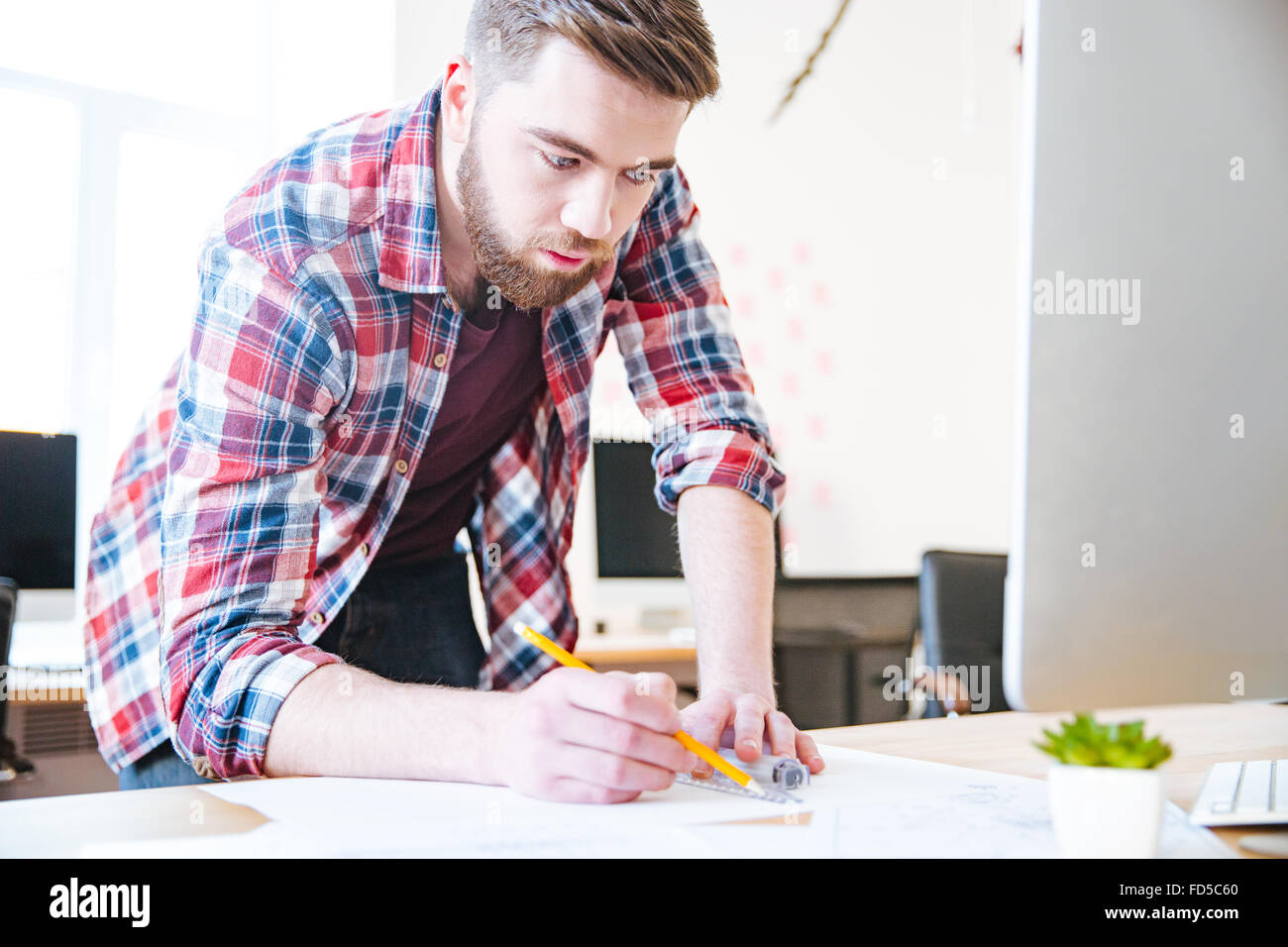 Concentrated handsome man in checkered shirt working and drawing ...