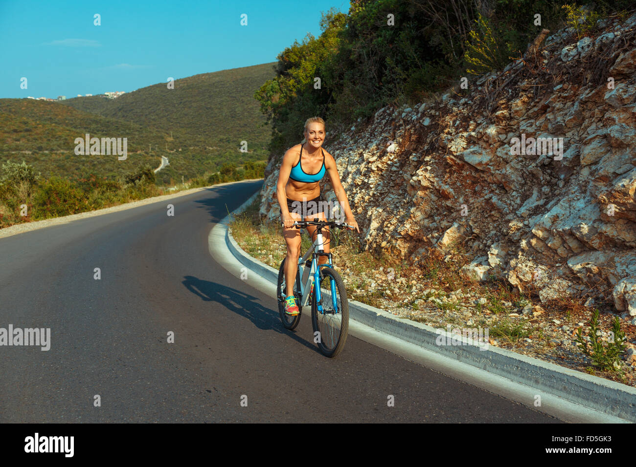 Happy woman cyclist riding a bike on a mountain road Stock Photo - Alamy