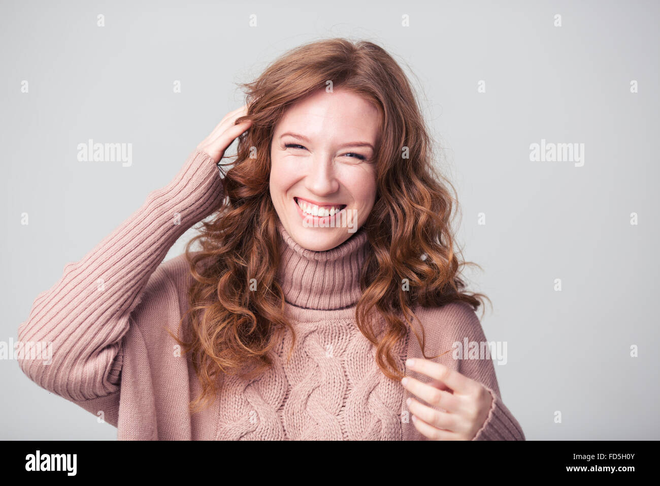 Portrait of a beautiful laughing woman looking at camera over gray ...