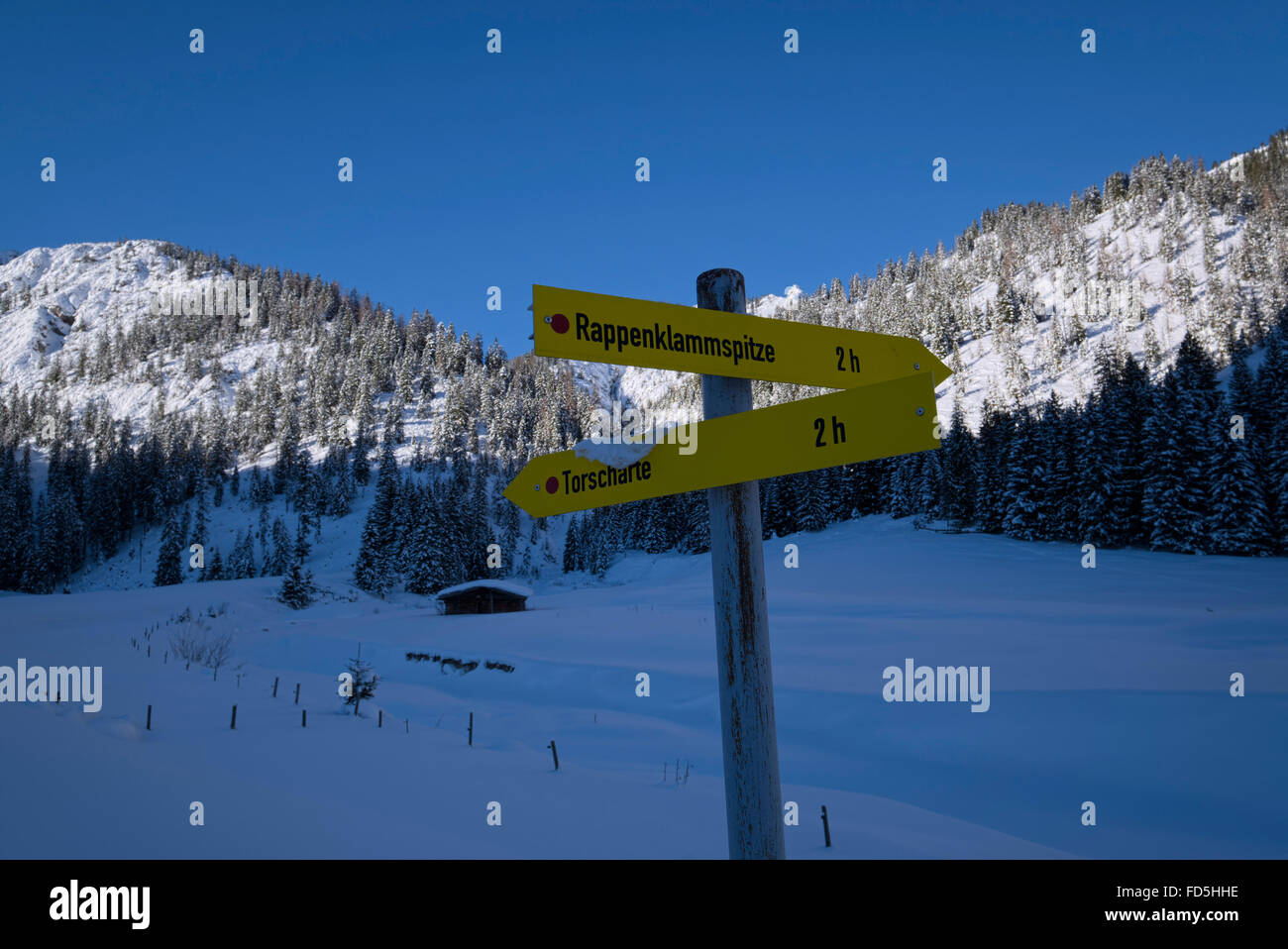 hiking signs and mountain hut surrounded by snowy mountains in winter ...