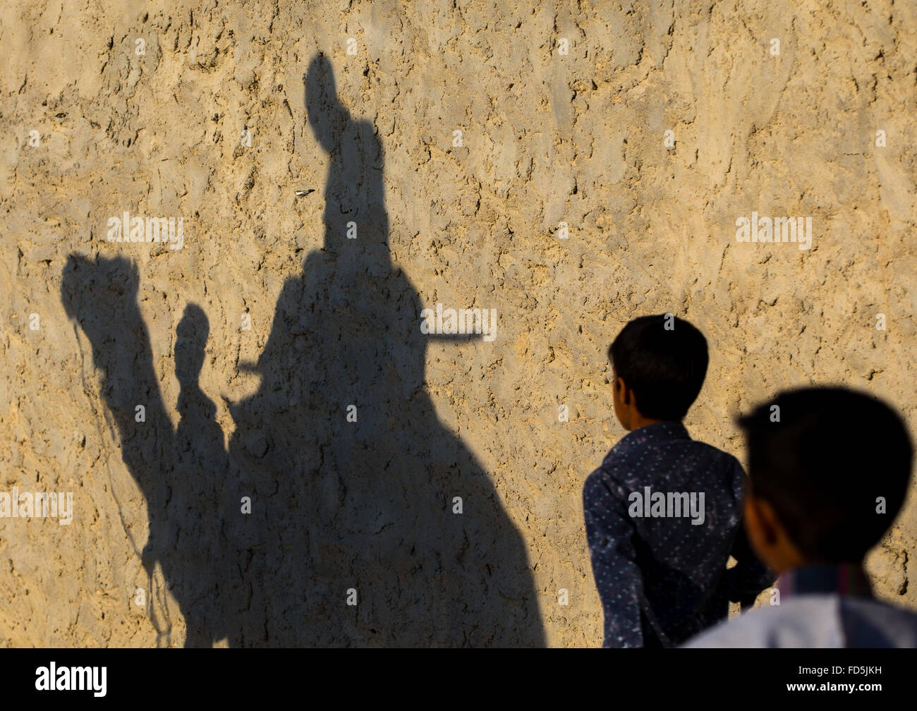 shadow on an adobe wall of the groom riding his camel during a wedding ...