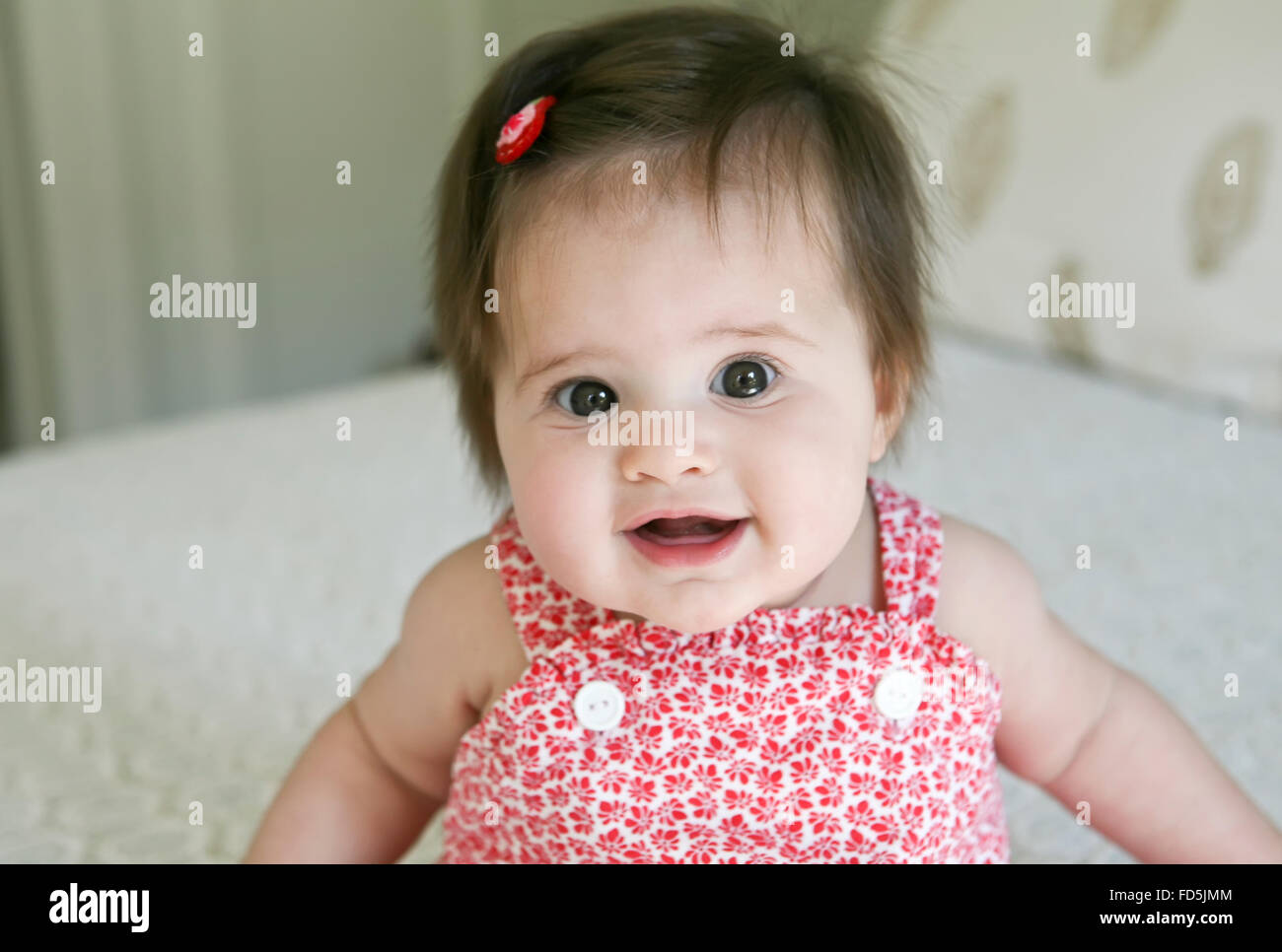 Precious, wide-eyed baby girl staring at the camera smiling Stock Photo ...
