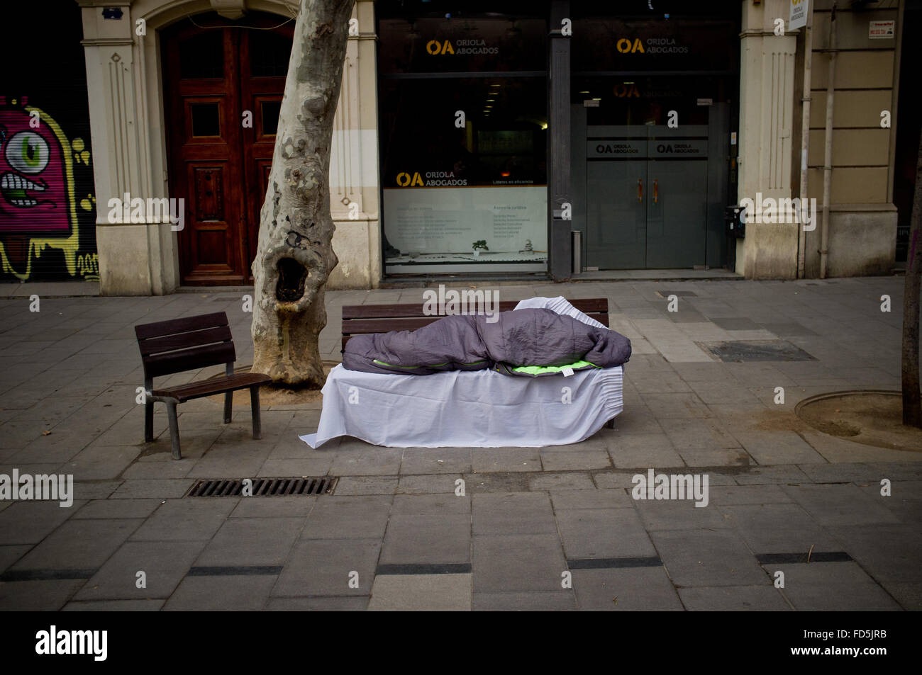 A homeless sleeps on a bench in Barcelona streets, Spain Stock Photo ...