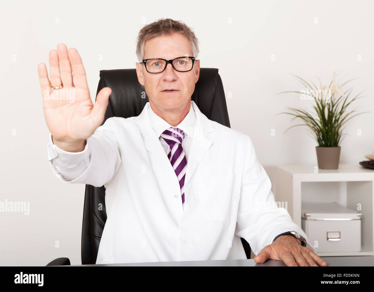 Serious Doctor Showing Hand Stop Sign While Sitting on Chair Stock ...