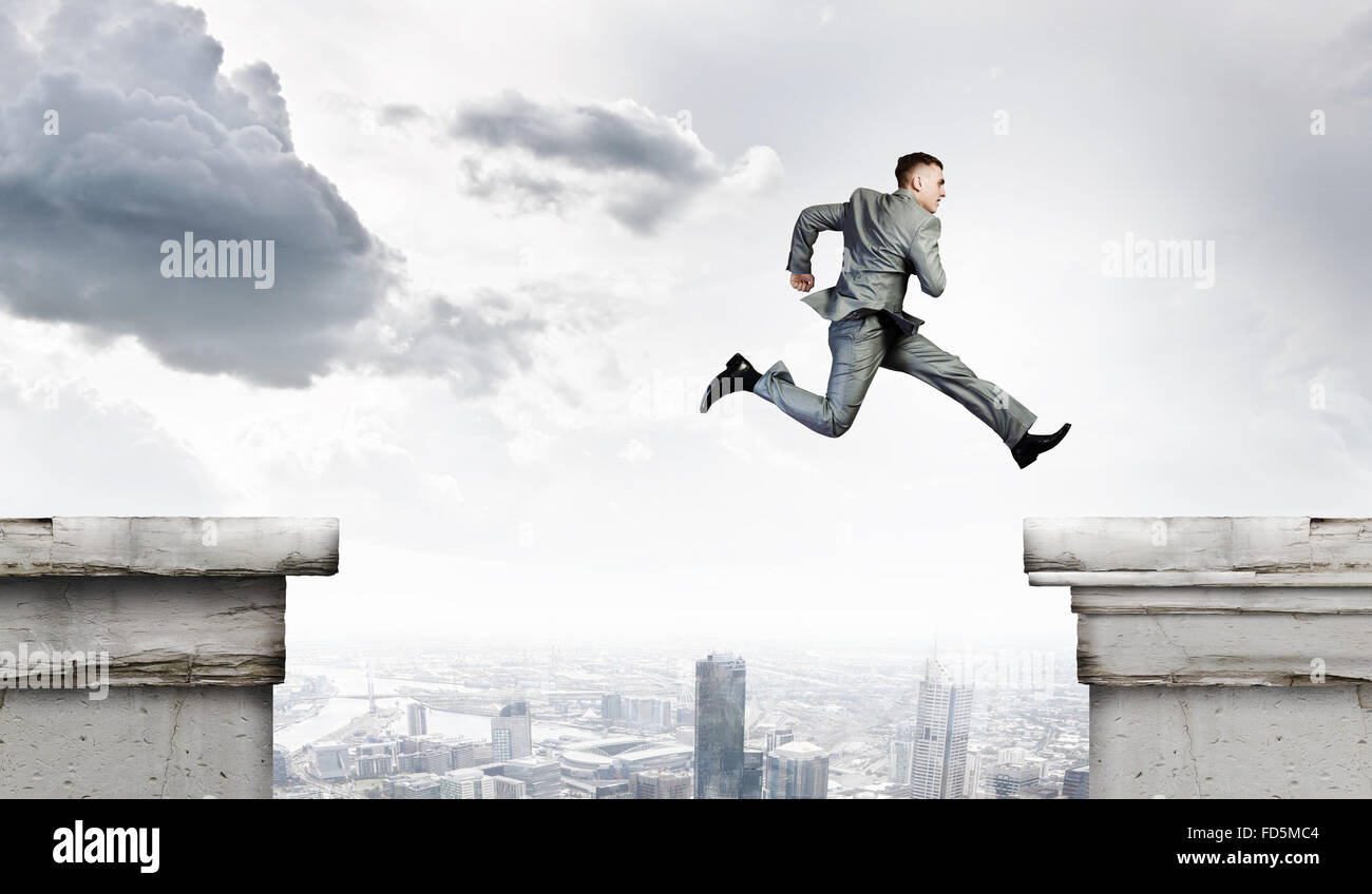 Image of young businessman jumping over gap in bridge Stock Photo - Alamy