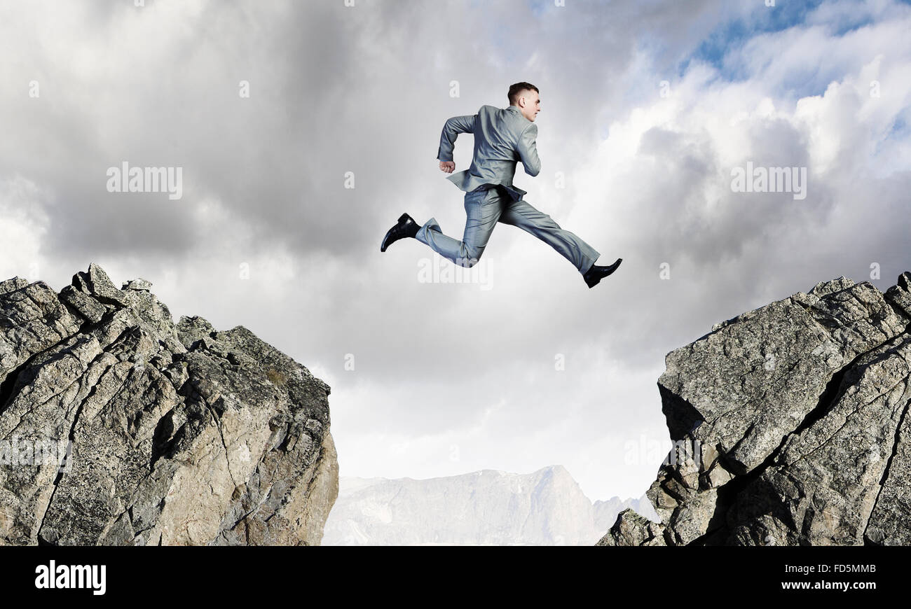 Image of young businessman jumping over gap Stock Photo - Alamy