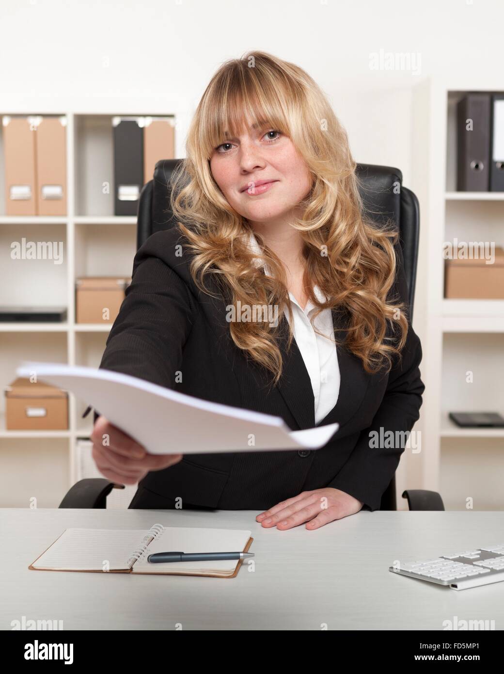 Beautiful businesswoman handing over paperwork extending her hand to ...