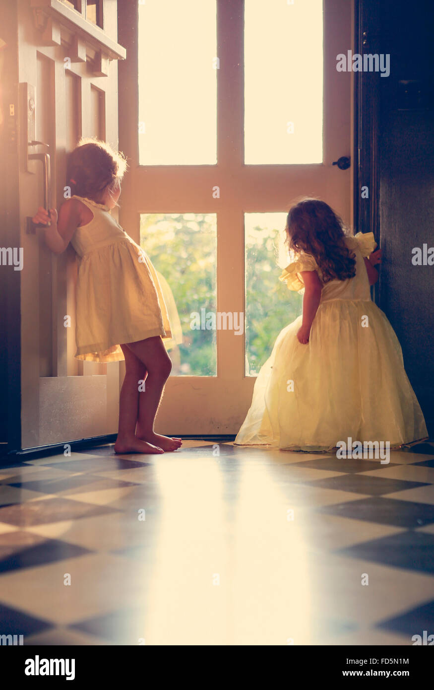 Two little girls in yellow dresses staring out their front door as the ...