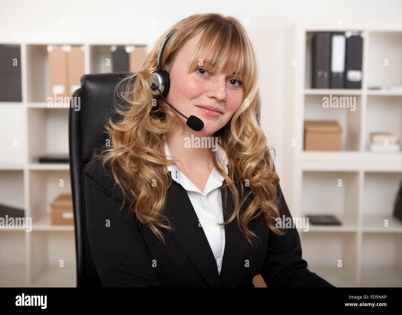 Friendly businesswoman wearing a headset looking at the camera with a ...