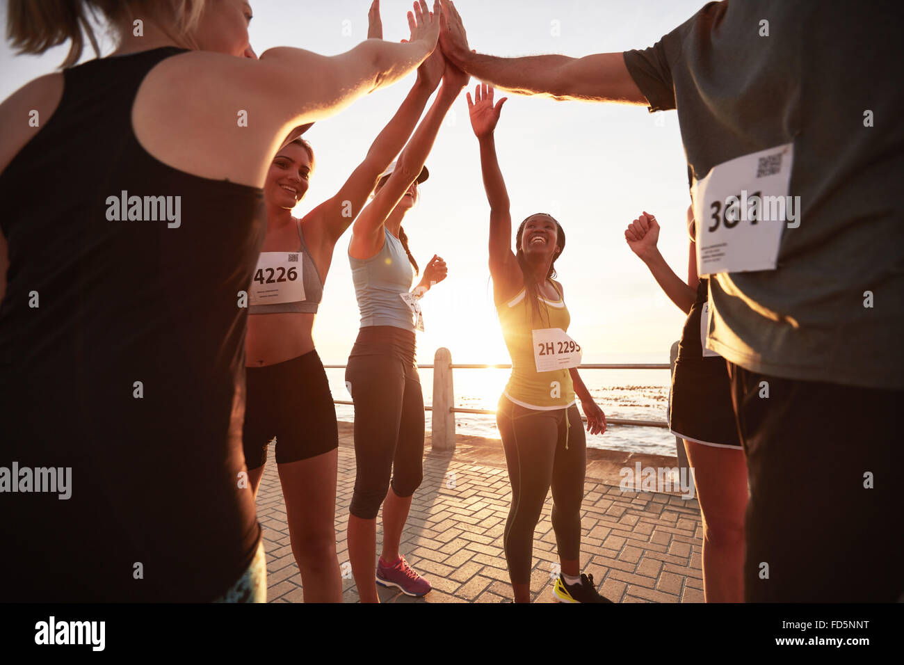 Shot of male and female runners high fiving each other after a race ...