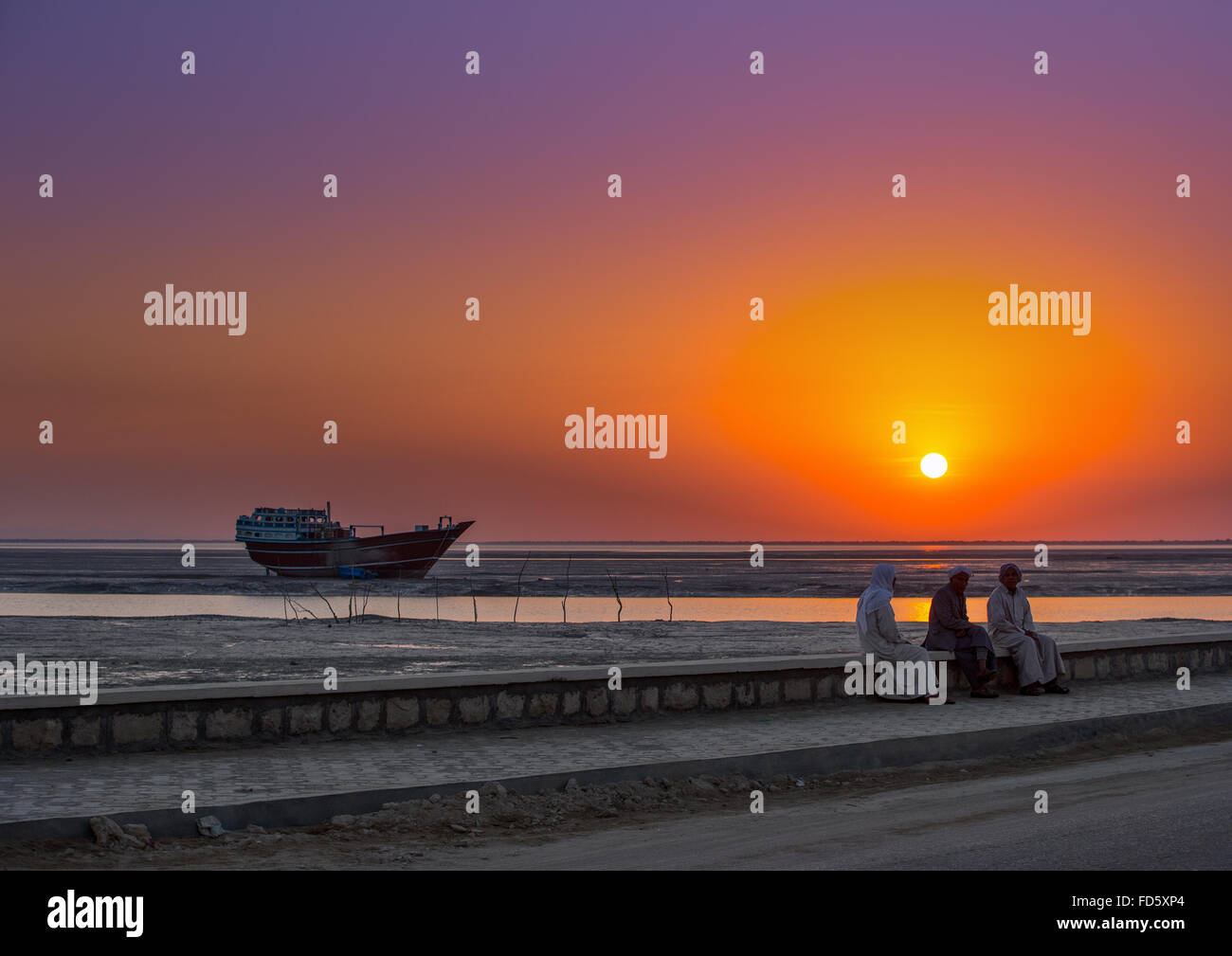 men dressed in traditional dress, sitting on a bench in front of a ...