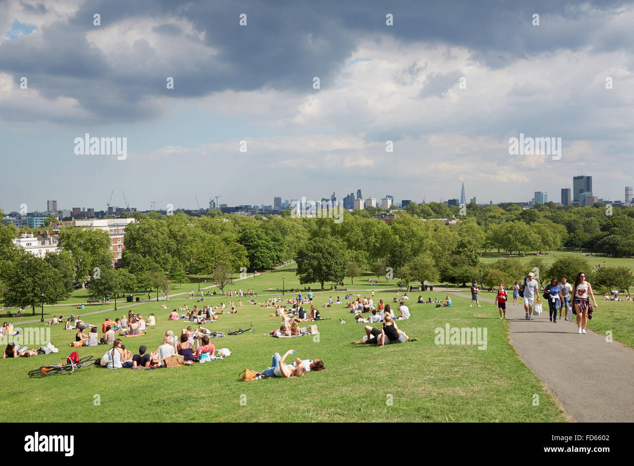 Primrose hill top with London city view and people relaxing in the park ...